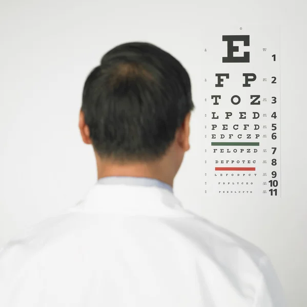 Asian man looking at eye chart - Stock Image - Everypixel