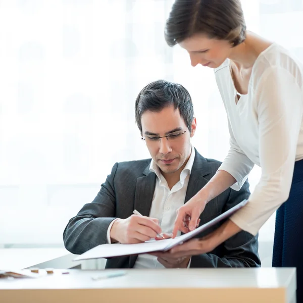 Businessman Signing a Document Hold by Secretary - Stock Image - Everypixel