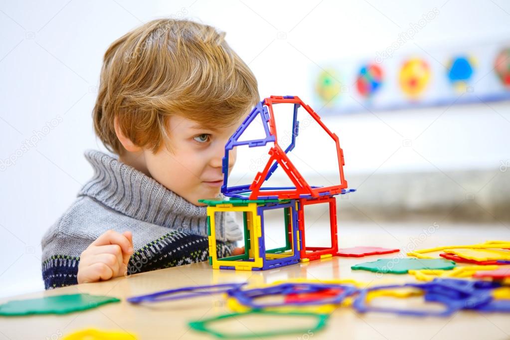Niño pequeño construyendo figuras geométricas con bloques de plástico 2023