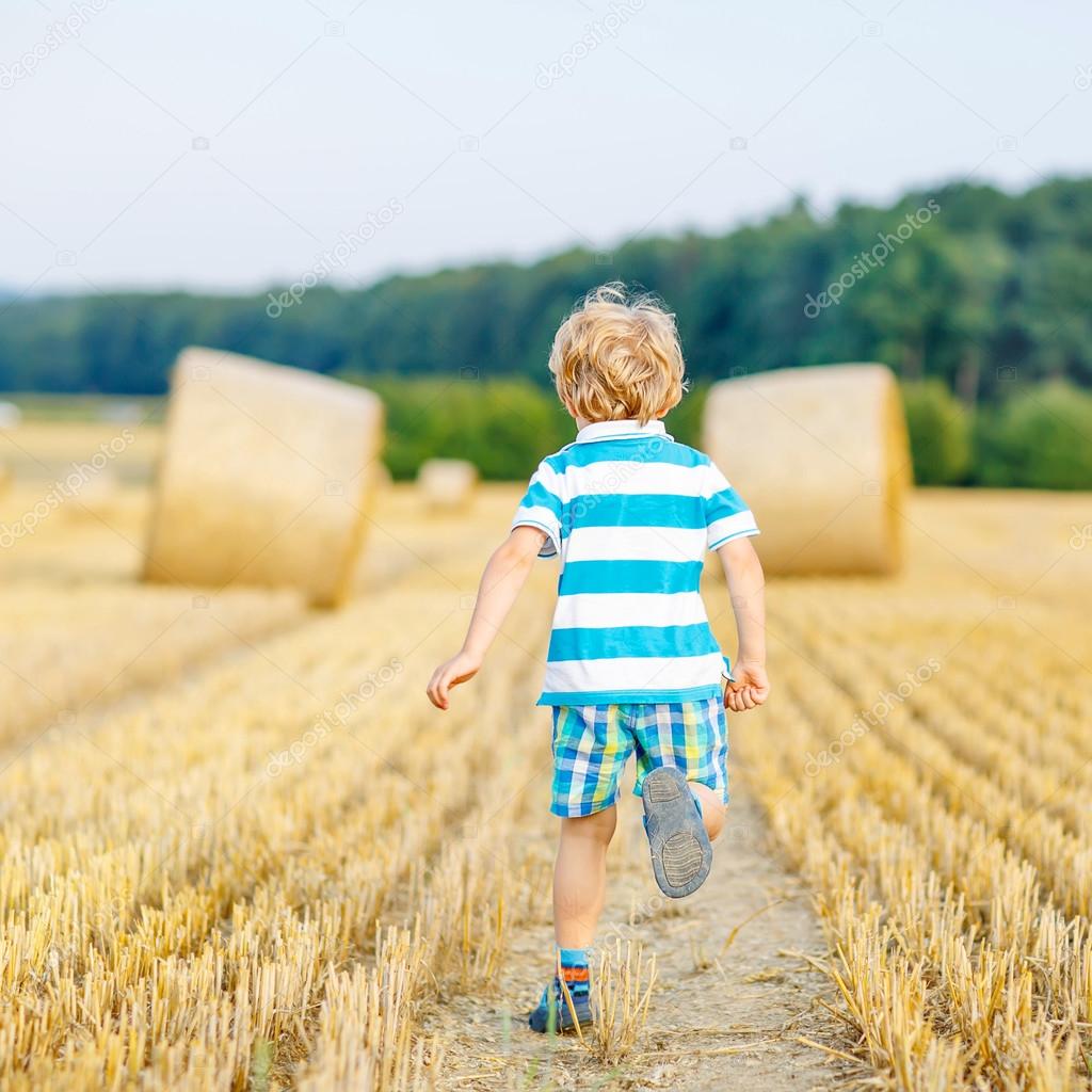 Little kid boy playing on hay field, outdoors Stock Photo by ...