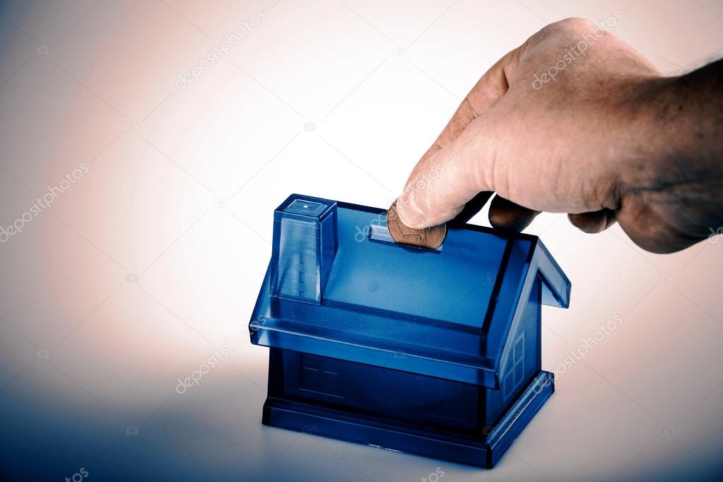 Blue House Money Box with man hand and coin on White Background Stock ...