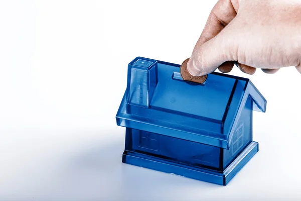 Blue House Money Box with man hand and coin on White Background Stock ...