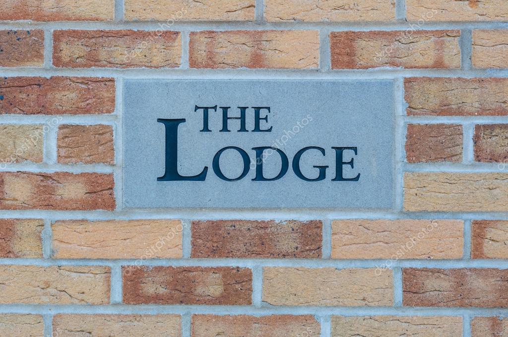 Sign 'The Lodge' on a brick wall — Stock Photo © kk_tt #67842857