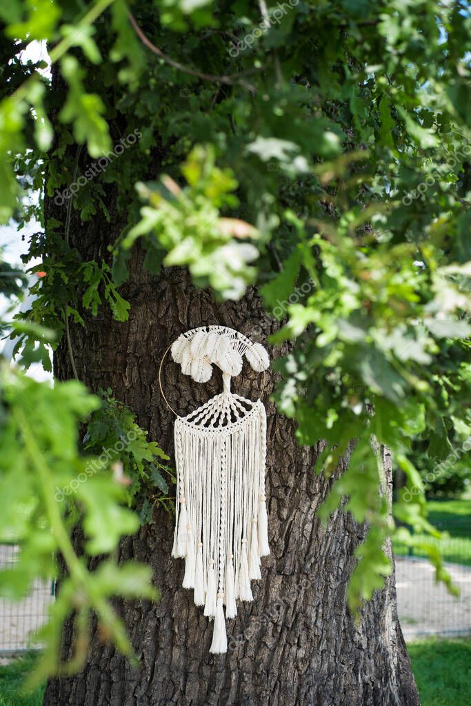 Un panel de macramé de mimbre redondo en forma de árbol con hojas con ...