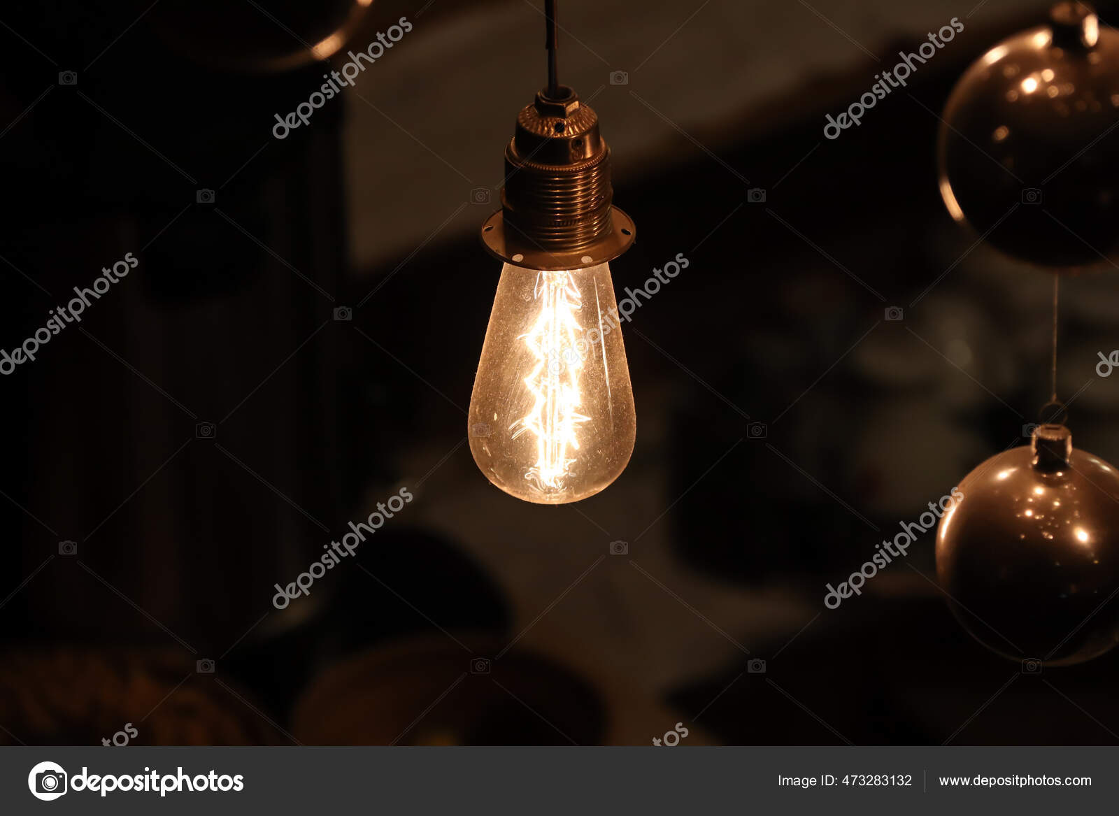 Old dusty incandescent lamp bulb on the wire shines in the dark and ...