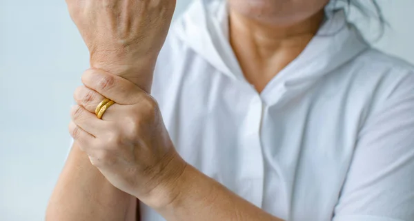 Mujer vestida de blanco usando la mano para sujetar la muñeca con dolor ...