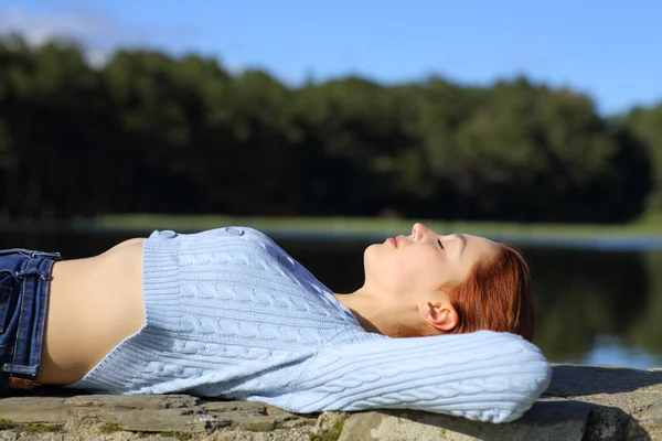 Side view portrait of a relaxed woman resting lying beside a lake in ...