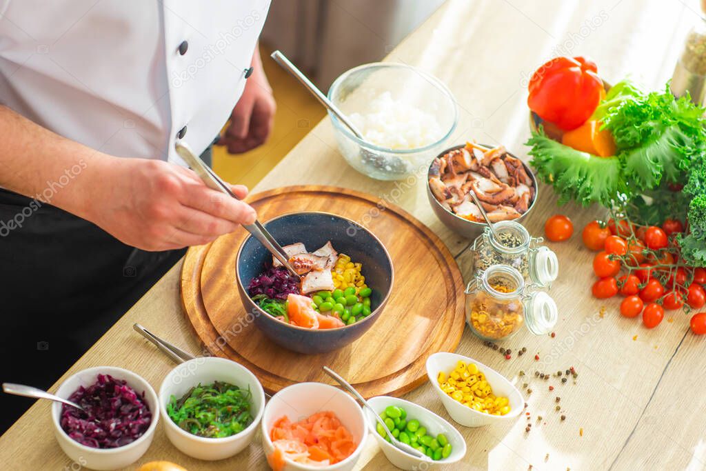 Young prepara un poke bowl en una cocina moderna. El hombre prepara ...