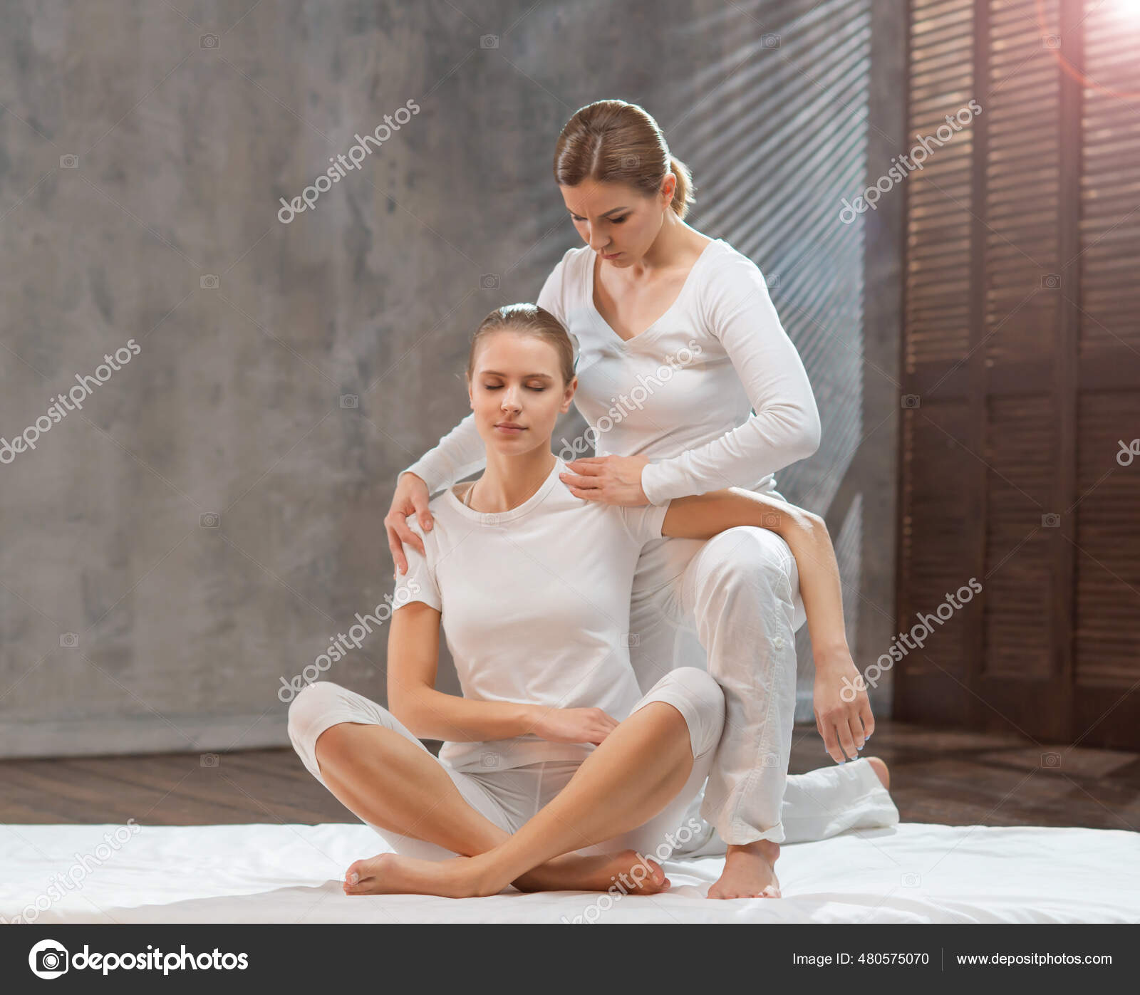 Professional masseur doing Thai massage. Therapist is making body stretching exercises to the ...