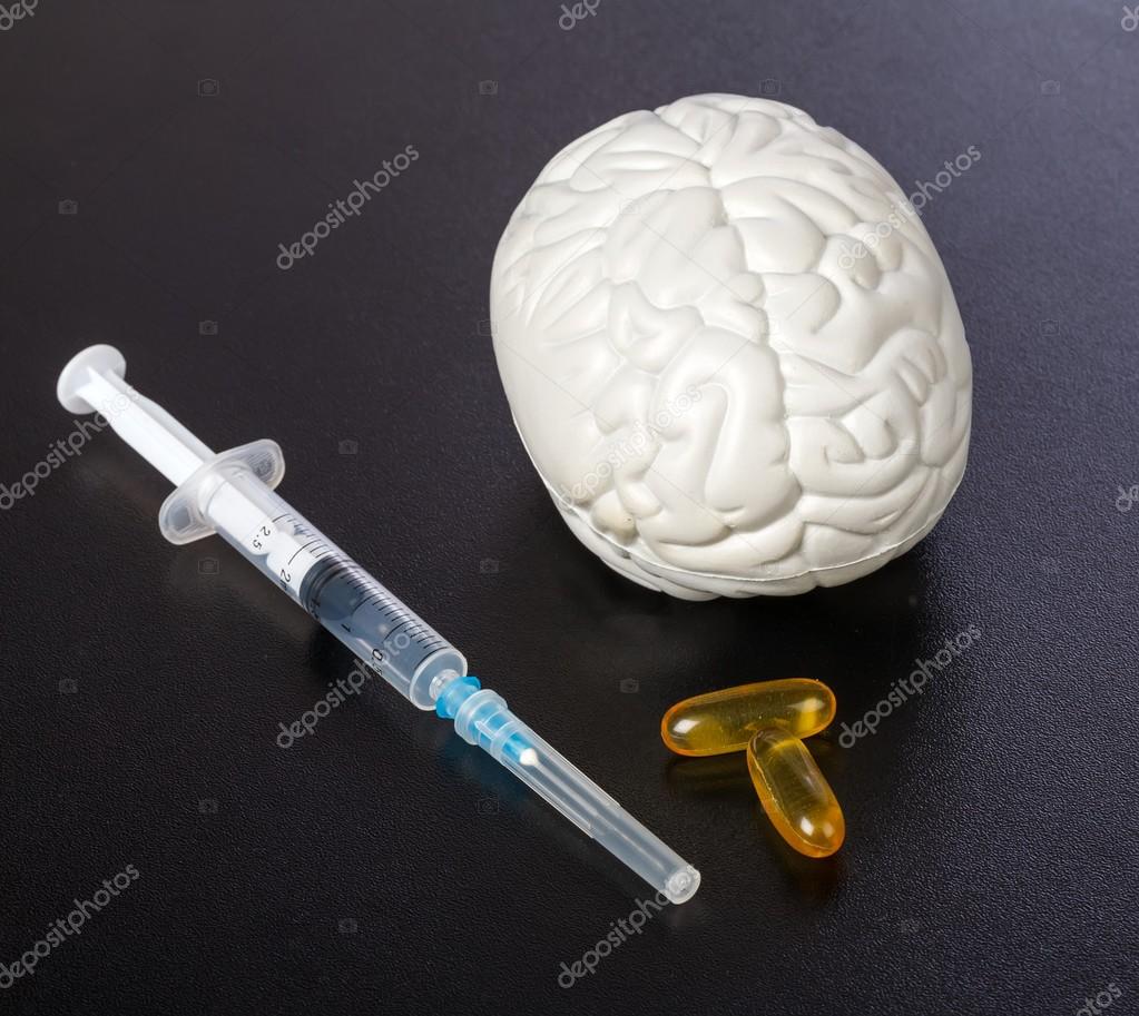 Plastic brain injection and omega 3 capsules on isolated black ...