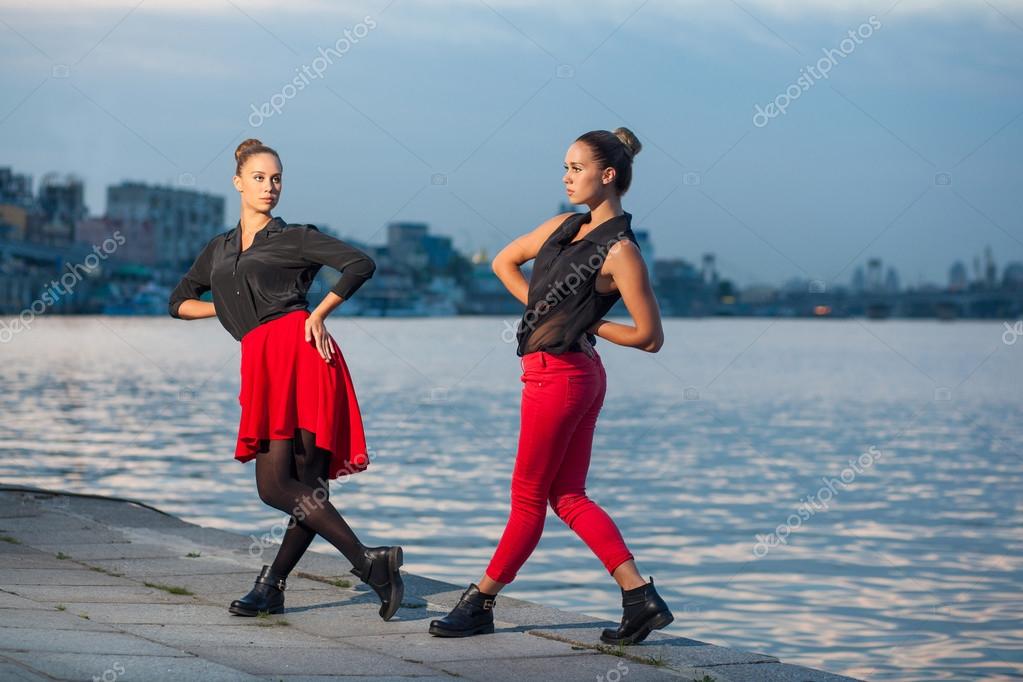 Two young beautiful twin sisters are dancing waacking dance in the city ...