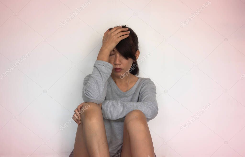 Mujer infeliz se sienta y abraza sus rodillas hasta el pecho, levantar la mano tocar la cabeza ...