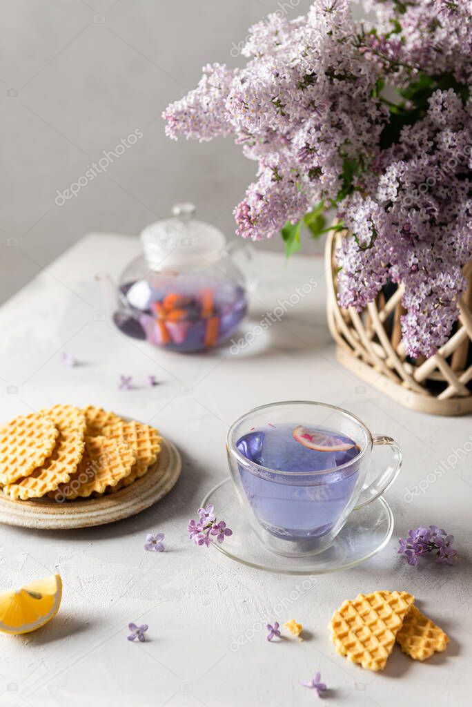 Taza de té morado con limón y un ramo de flores de color lila sobre un ...