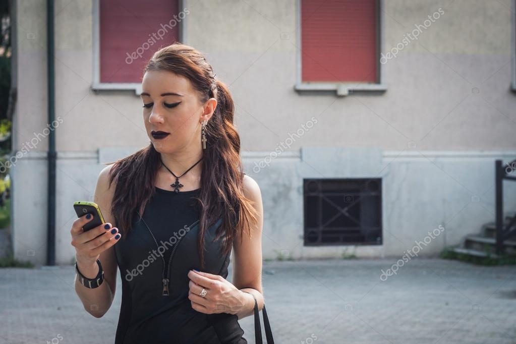 Pretty goth girl using phone in a city park Stock Photo by ©tinx 52616523