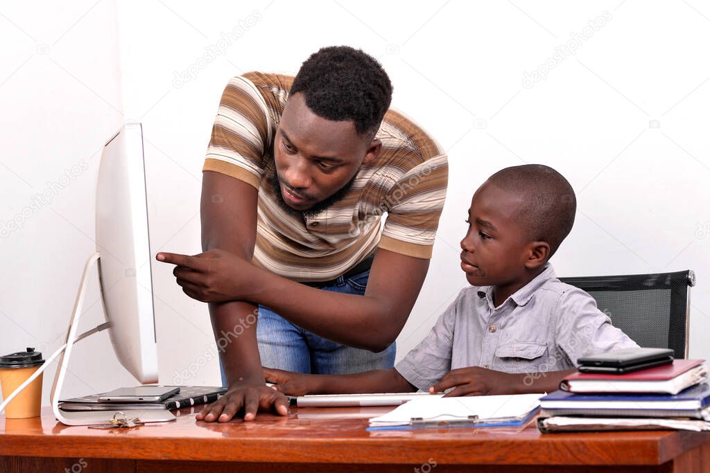 a young father in a T-shirt standing in office guiding his son to work ...