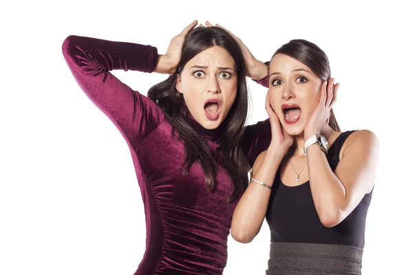 Shocked women friends posing isolated over white wall background on a ...