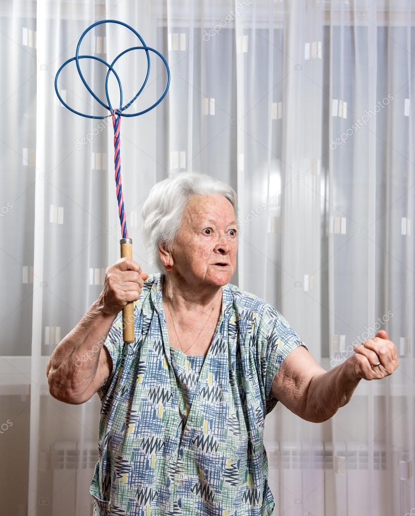 Old angry woman threatening with a carpet beater — Stock Photo ... Old angry woman threatening with a carpet beater — Stock Photo ...