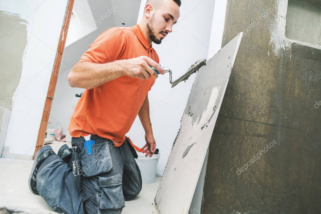 vista de ngulo bajo del hombre la instalaci n de azulejos en la pared. casa interior renovaci n 2024