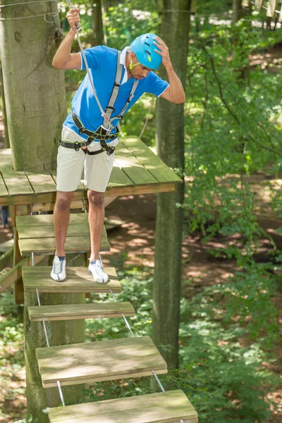 Man is afraid of heights at high rope court - Stock Image - Everypixel