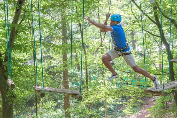 Man jumping while climbing in high rope course - Stock Image - Everypixel