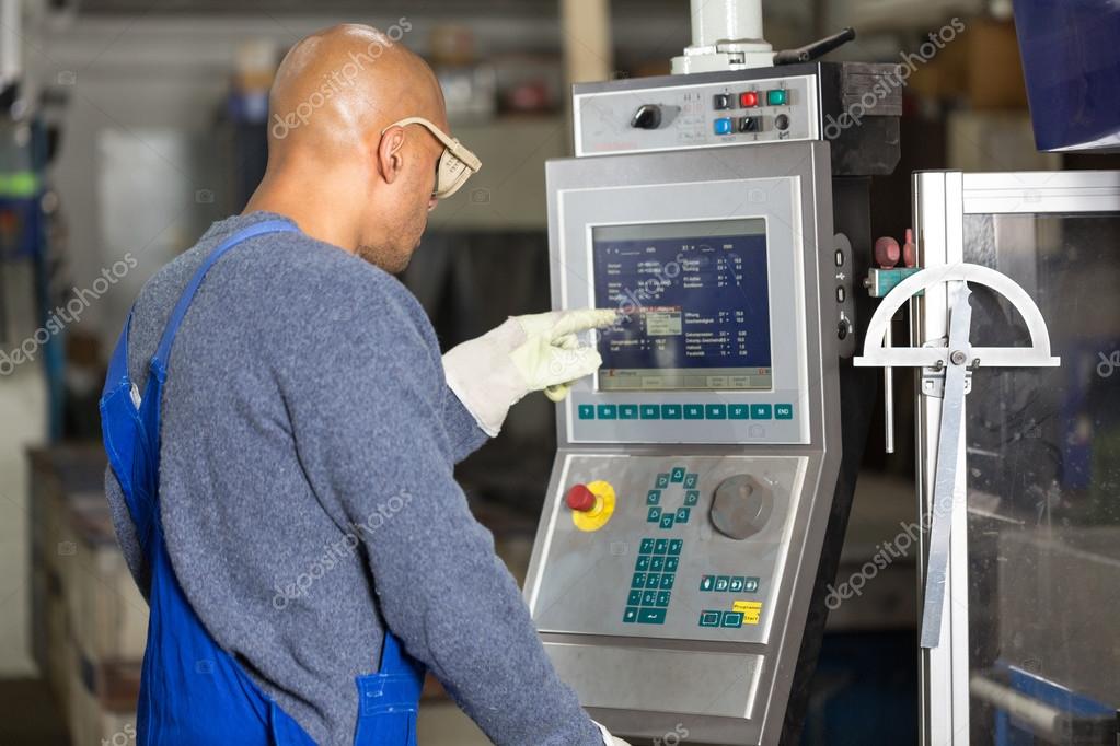 Trabajador operando una máquina con panel de control 2024