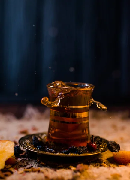 Turkish tea with splashes is poured from a teapot into a cup of hot ...