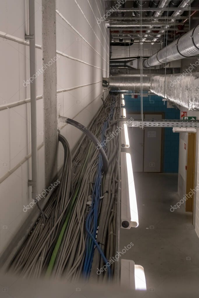 En el pasillo de un gran edificio, cables eléctricos cuelgan del techo ...
