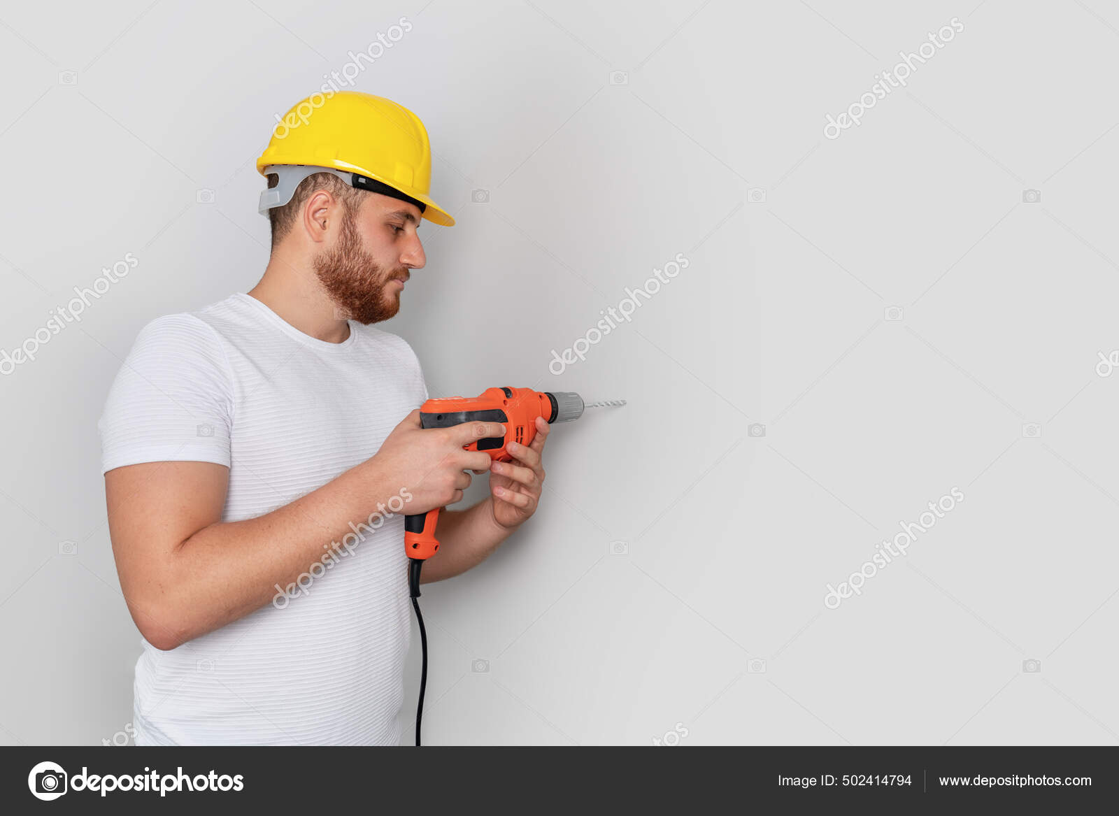 Man worker is drilling a hole on the wall for construction or ...