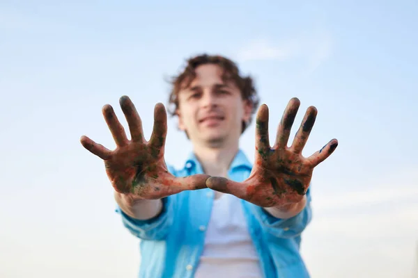 Close-up picture of male artist pointing his stained with paint hands ...