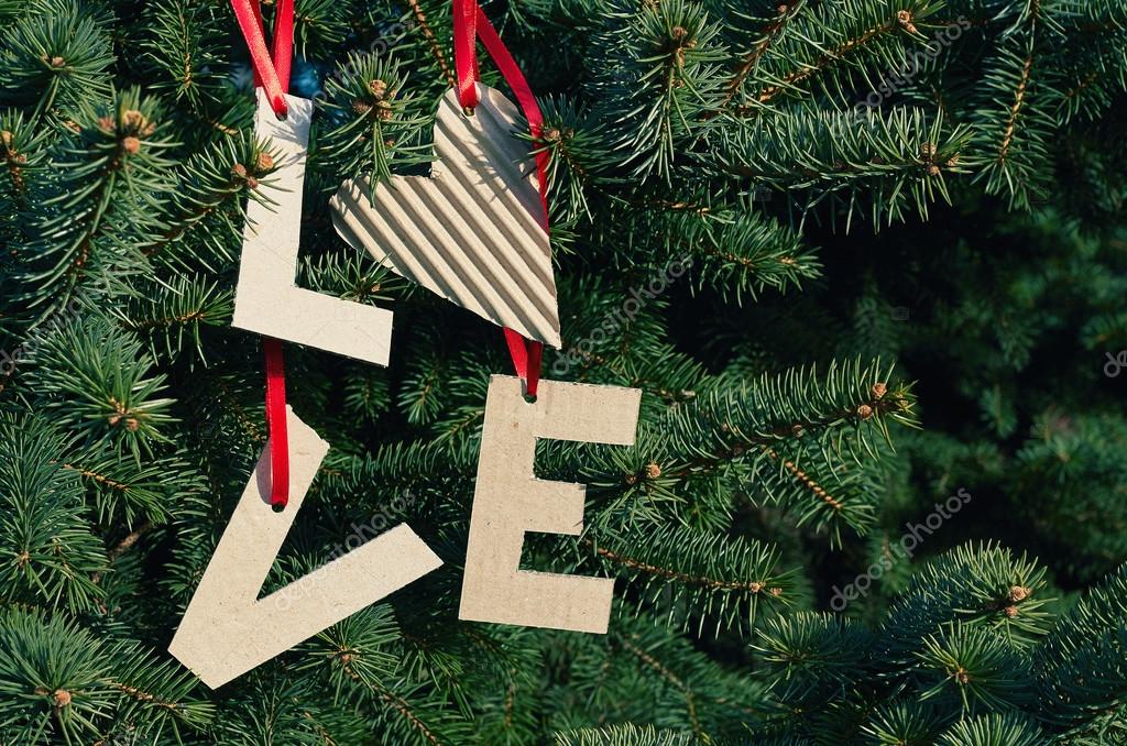 Cardboard LOVE letters hanging on red stripes on green pine tree ...