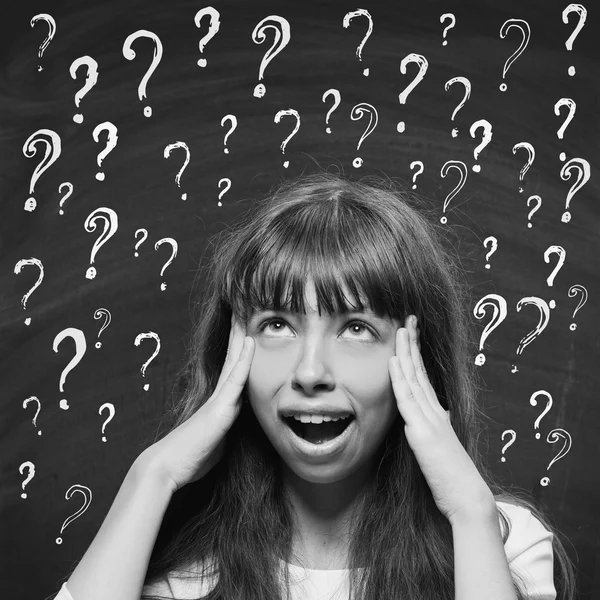 Young woman with doubtful expression and question marks over her head ...
