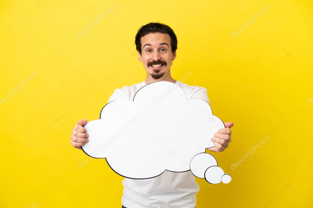 Молодой кавказский человек, изолированный на желтом фоне, держит ...