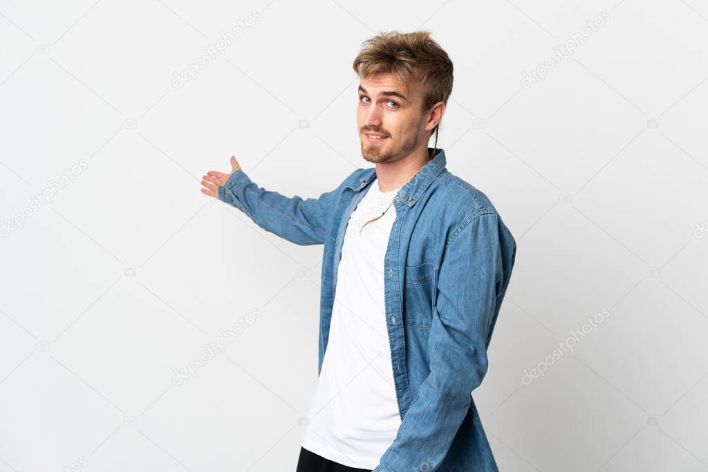 Joven hombre guapo aislado sobre fondo blanco extendiendo las manos a ...