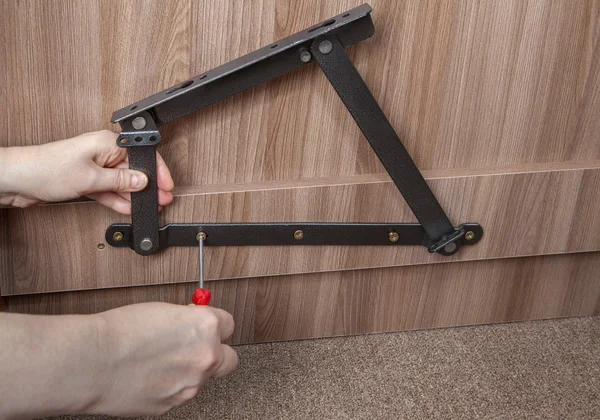 Installation of steel spring lifting mechanism on wooden bed frame ...