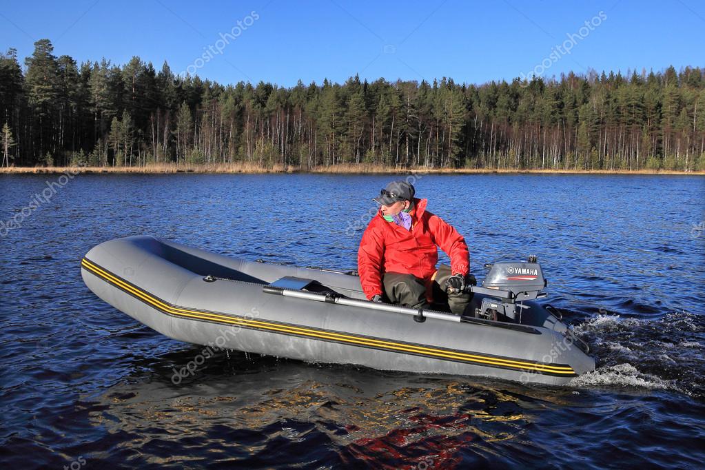 Fisherman controls gray inflatable rubber boat with an outboard motor ...
