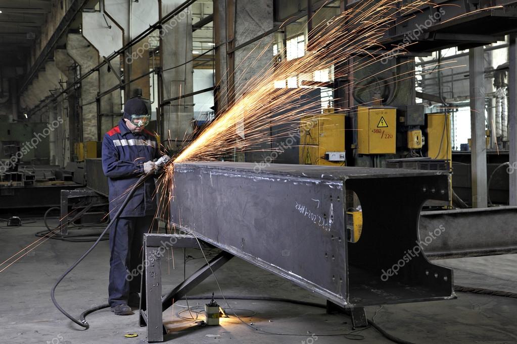 Metalworkers polishing welds metal structures, producing fountain of ...