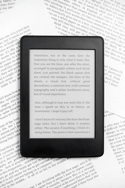 Electronic reader with the screen on and a text on it, on sheets of ...