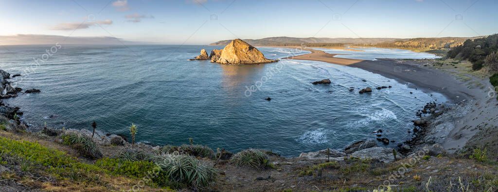 Una playa idílica y salvaje con una isla rocosa y una lengua de arena ...