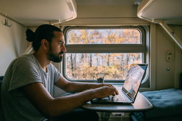 Man with laptop on the train. Portrait. Young handsome guy works ...