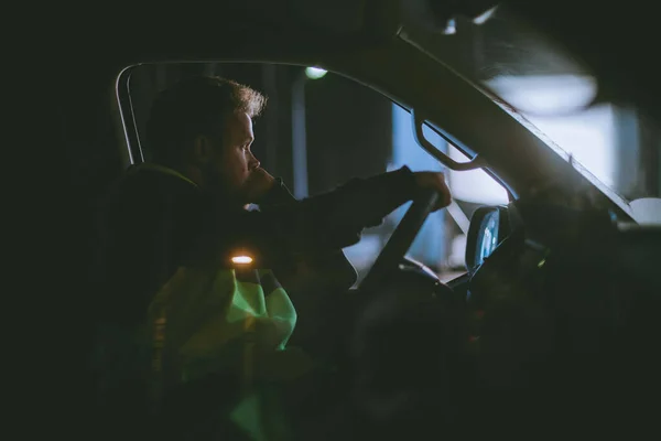 The man is alone driving a car at night. Young serious focused guy is ...