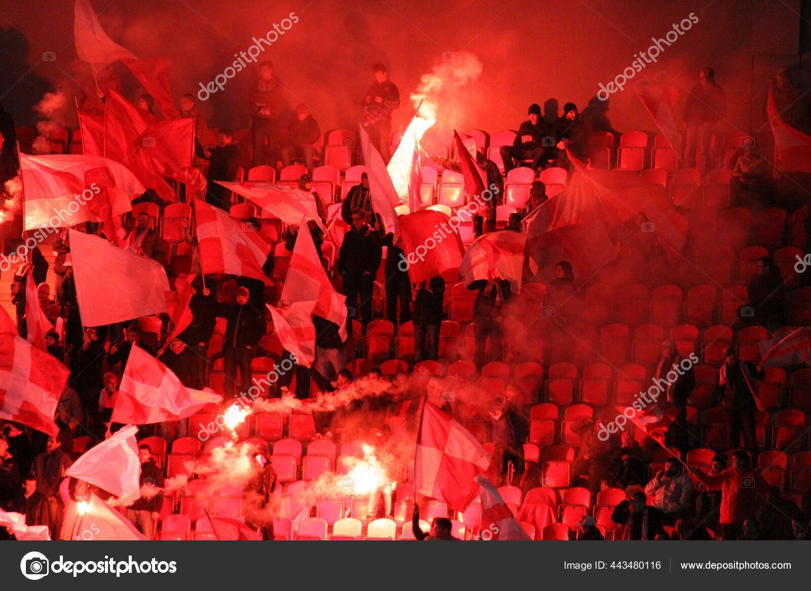 Hooligans fans on tribune using pyrotechnics and fire. Yelling, flags ...
