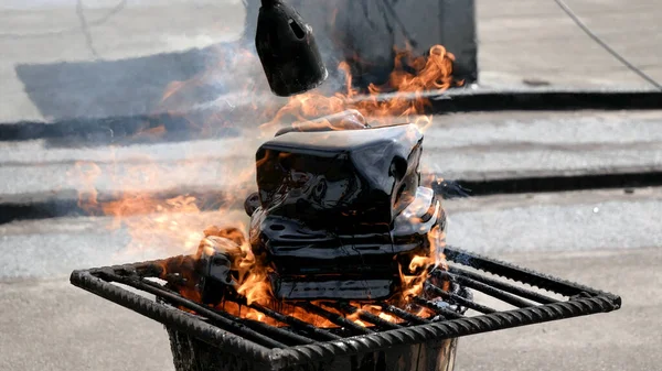 A worker melts tar with help of gas burner and fire. Pieces of bitumen ...