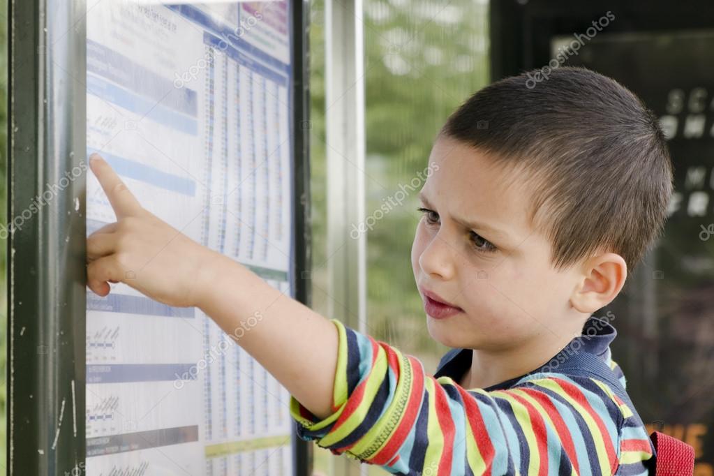 Child reading timetable at bus stop Stock Photo by ©pavsie 81456360