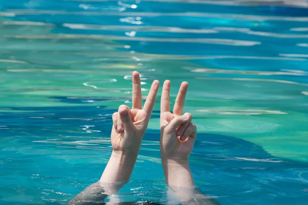 A hand of a drowning person stretching out of the water in a swimming ...