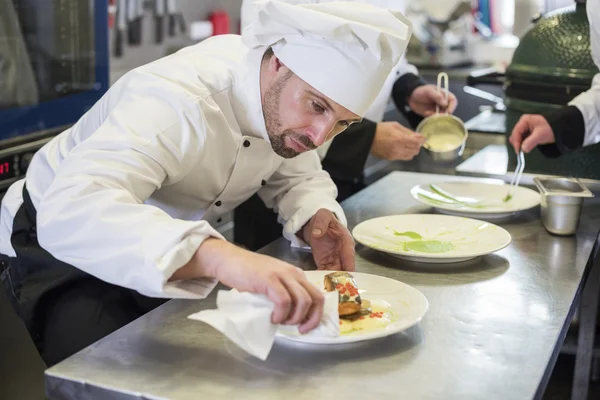 Chef cleaning plate before serving meal. - Stock Image - Everypixel