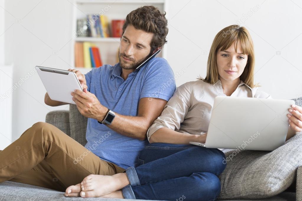 Digital geek couple on sofa at home Stock Photo by ©LDProd 86769146