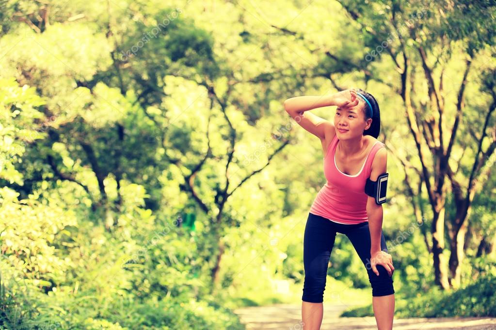 Tired female runner taking a rest after running hard in countryside ...
