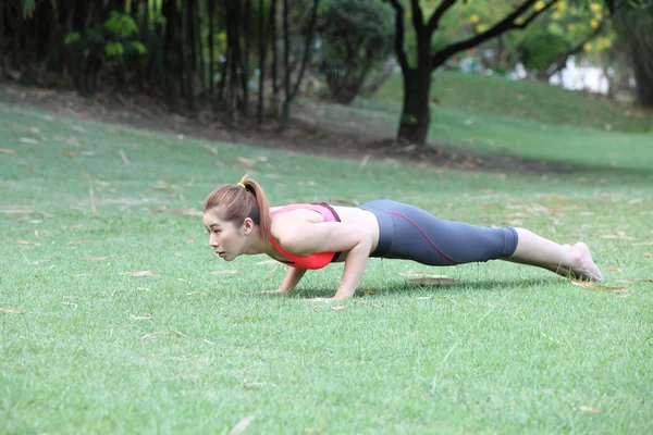 Fitness woman doing push-ups during outdoor cross training worko ...