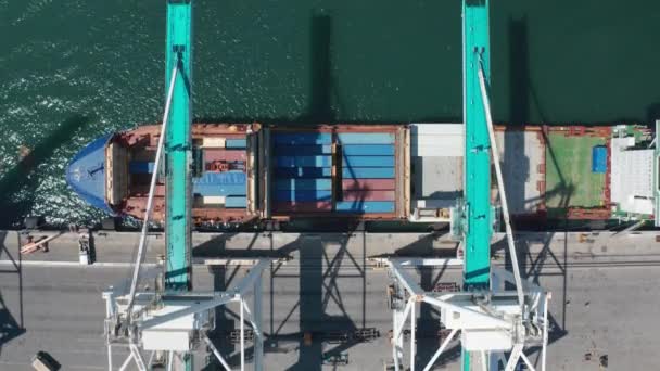 4K aerial view industrial crane unloading containers from ship, water ...