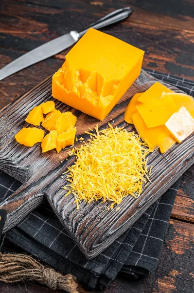 Slices of Cheddar Cheese on a wooden cutting board. black background ...